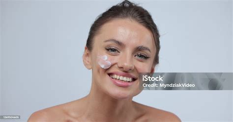 젊은 여자는 그녀의 병아리에 크림을 넣어 카메라에 웃음 화장품을 사용하여 예쁜 여성 모델 스킨 케어 컨셉 갈색 머리에 대한 스톡 사진 및 기타 이미지 Istock