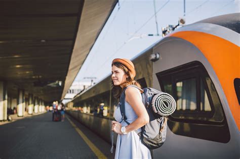 테마 철도 및 여행 여름에 드레스와 모자관광 고립 매트를위한 배낭 과 장비와 기차역 기차 배경에 서있는 이빨이 있는 미소를 가진 초상화 젊은 백인 여성 가방에 대한 스톡