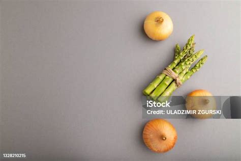 회색 파스텔 배경에 신선한 녹색 아스파라거스와 양파의 무리 상단 보기 플랫 레이 복사 공간 수확 건강 채식주의 음식 개념