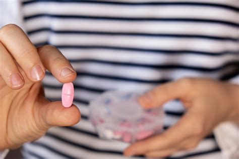 여자 분류 알약 주최자 주간 샷 매일 흰색 분홍색 약물과 캡슐로 약을 복용하기위한 정제의 복용량과 의료 알약 상자의 근접 촬영 집에서 매일 비타민을 섭취하는 젊은 여성 건강