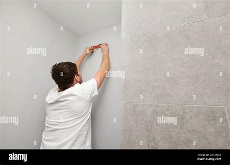Male Worker Using Spirit Level Tool And Pencil While Checking Wall Level Before Repair Works