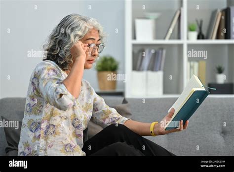Elderly Woman Trying To Read Book Having Difficulties Seeing Text
