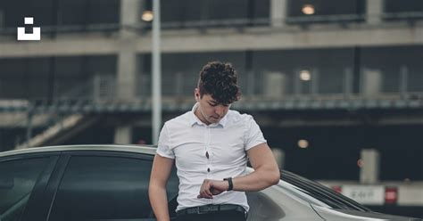 흰색 티셔츠와 검은 바지를 입은 남자가 은색 차에 앉아 있다 사진 Unsplash의 무료 디모인 이미지