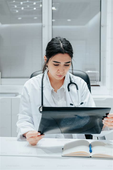 하얀 실험실 코트를 입은 여자가 노트북에 글을 쓰고 있다 사진 Unsplash의 의사 이미지