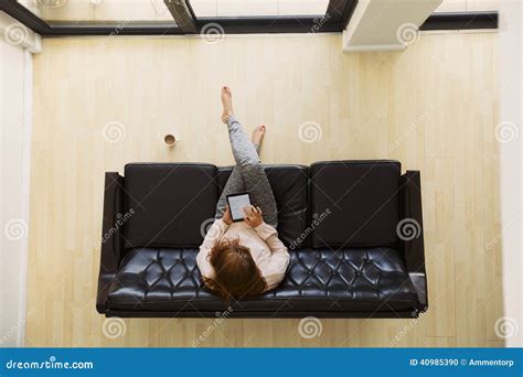 Young Woman Sitting On A Sofa With Digital Tablet Surfing Online Stock