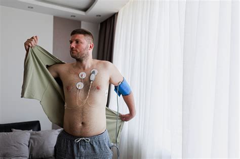 심장 강화 모니터를 가진 젊은 남자가 옷을 입습니다 심장의 작업에 대한 연구 심장학 홀터 모니터 의료 진단 건강 관리 병원 심전도 센서 심전도 및 혈압 측정 가정 생활에