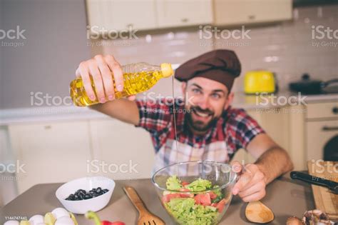 좋은 및 Positice 수석 테이블에 부엌에서 스탠드와 기름 병을 보유 하 고 있습니다 그는 샐러드와 함께 그릇에 일부를 쏟아 붓는 다 그는 행복 하 고 흥분 보인다 가정