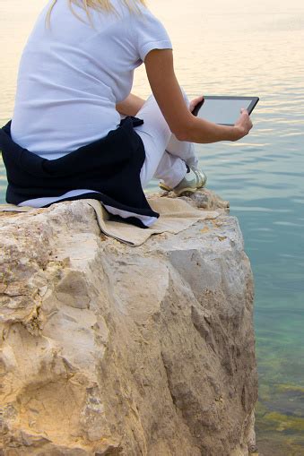 해변 절벽 가장자리에 앉아 디지털 태블릿을 사용 하는 매력적인 젊은 여자의 자르기 보기 프리랜서 작업 여행자 개념 텍스트를 위한 공간 건강한 생활방식에 대한 스톡 사진 및