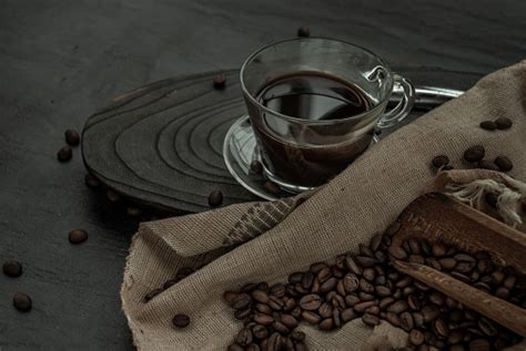 나무와 어두운 돌 배경에 오래된 나무 국자와 커피 콩으로 가득 찬 커피와 커피 콩 한 잔 텍스트에 대한 복사 공간이 있는 상단의 경사 보기입니다 갈색에 대한 스톡 사진 및