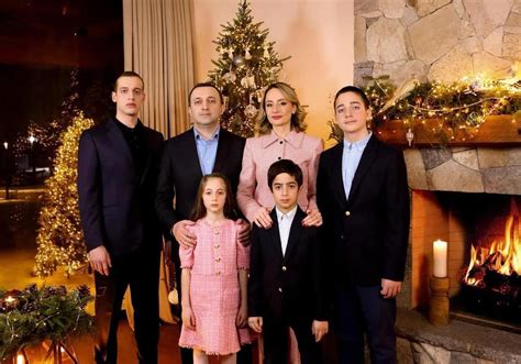 ოჯახური ფოტოსესია ორი ნაძვის ხის ფონზე ღარიბაშვილების შინაური საახალწლო გარემო მშობლები