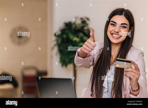 Portrait Of Delighted Young Brunette Woman Updating Her Bank Account From Her Office Stock