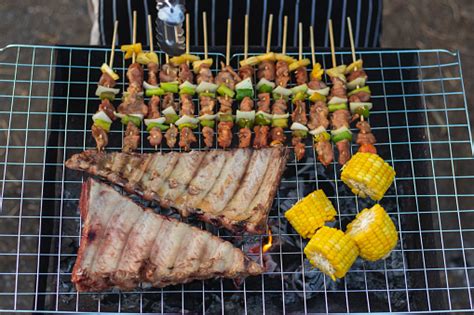 바베큐 파티를 위한 고기와 꼬치 재료를 그릴에 올려 바베큐를 요리하고 오늘 밤 가족이 바베큐 파티에 참여할 수 있도록 준비합니다