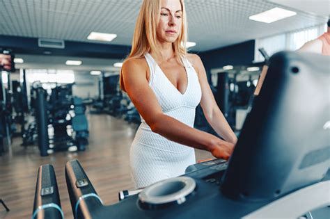 체육관에서 러닝 머신에서 달리는 흰색 트랙 슈트를 입은 성인 여성 40 44세에 대한 스톡 사진 및 기타 이미지 40 44세