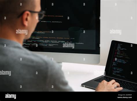 Programmer Working Behind The Desk Analysing Code On The Black Screen
