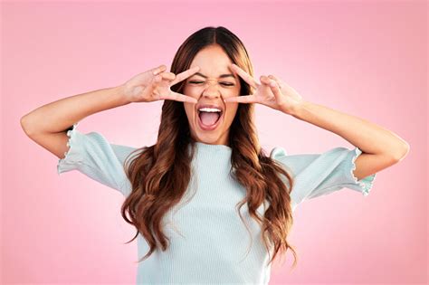 평화의 표시 비명을 지르며 스튜디오에서 분홍색 배경에 고립된 재미있는 여자 손 제스처 고함 미친 아름다움과 행복한 혼혈 여성 모델 만화 표현 또는 이모티콘을 위한 V 기호