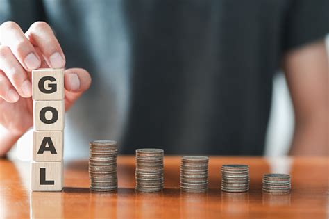 책상 위에 동전을 쌓아 놓은 나무 큐브 상자 Goal을 놓는 사업가 저축 돈 은행 예금 이자 징수 및 목표 달성 개념 사업 성장 재무 관리의 상승 추세 개념에 대한 스톡