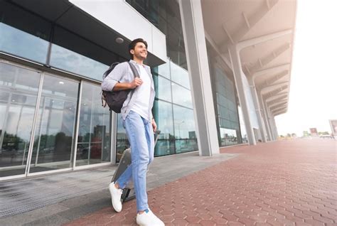 Premium Photo Happy Millennial Man Walking With Luggage Out Of Airport Building