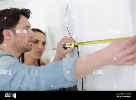 Man And Woman Measuring The Wall With A Measuring Tape Stock Photo Alamy