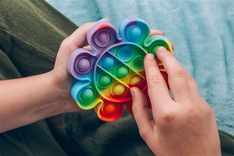 무지개 팝을 사용하여 소년의 손을 닫습니다 그것은 안절부절 장난감 거품 안절부절 감각 장난감을 밀어 세척 및 재사용 실리콘 스트레스 릴리프 장난감 특별한 도움이 필요한