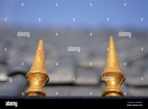 two golden triangular shaped objects with sharp ends and a blurry blue