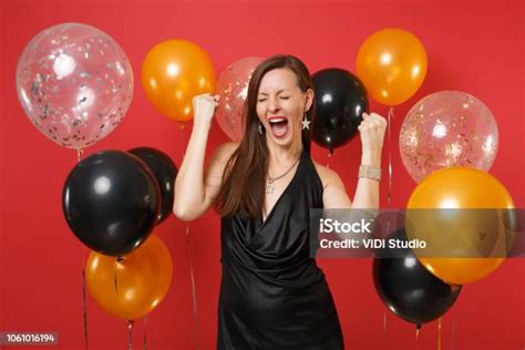 작은 검은 드레스 비명 축 하에 밝은 빨간색 배경에 공기 풍선에 우승자 몸짓을 하 고 좋아 라 젊은 여자 성 발렌타인의 날 해피 뉴가 어 생일 이랑 휴일 파티 개념 2019