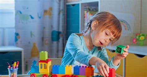 아이 방에서 다채로운 큐브가 있는 어린이 플라스틱 장난감 기차를 가지고 노는 어린 소녀 아이들을 위한 가정 활동 사진