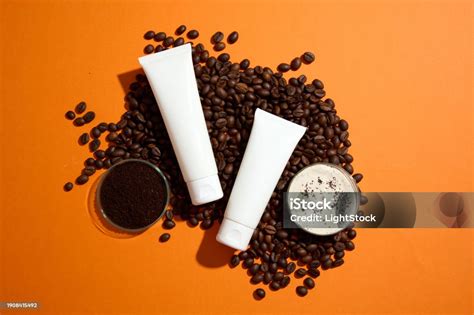 커피 원두의 성분으로 유기농 제품을 광고하기 위한 모형 장면 주황색 배경에 커피 원두 찌꺼기 크림 질감이 있는 두 개의 플라스틱 튜브가 표시됩니다 상의 View 0명에 대한
