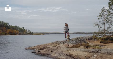 빨간색과 흰색 격자 무늬 셔츠를 입은 남자가 수역 근처의 갈색 바위에 서 있다 사진 Unsplash의 무료 회색 이미지