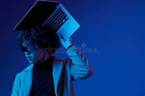 Portrait Of A Stylish Male Hacker With A Laptop And Futuristic Glasses In Blue Light Cyber