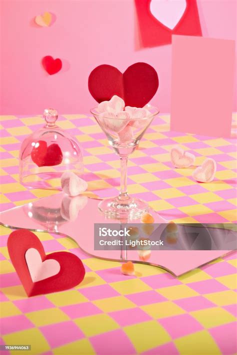 칵테일 잔에 담긴 하트 모양의 마시멜로 젤리 캔디 종이 하트 카드 아크릴 시트 유리 돔 커버가 함께 제공됩니다 광고를 위해 분홍색노란색 체크 무늬 표면에 설정합니다 개념에