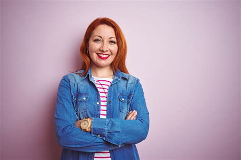 아름다운 빨간 머리 여자 데님 셔츠와 스트라이프 티셔츠 위에 고립 된 분홍색 배경 행복 한 얼굴 카메라를 보고 교차 팔 미소 긍정적 인 사람 T 셔츠에 대한 스톡 사진 및