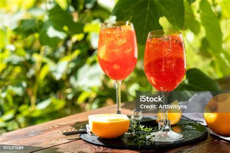 오렌지와 함께 큰 와인 잔에 두 개의 아페롤 스프리츠 칵테일 여름 이탈리아 신선한 알코올 차가운 음료 포도밭 배경의 햇볕이 잘 드는 정원 각얼음에 대한 스톡 사진 및 기타