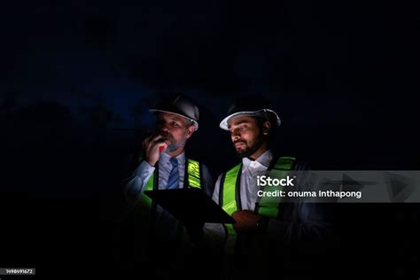 Sspeciallist 엔지니어는 현장 라인에서 밤에 열심히 일합니다 안전 조끼와 Ppe를 착용한 선임 관리자와 엔지니어는 밤에 노트북과 무전기로 작업합니다 2명에 대한