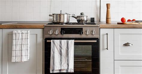 새 집에 현대적인 문과 스테인레스 스틸 가전제품이 있는 세련된 회색 주방 인테리어 스칸디나비아 스타일의 주방 디자인 녹색 식물 장식 스토브 굴뚝 음식 조리 사진