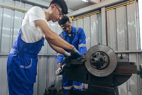 금속 선반 기계를 사용하는 다양성 정비사 또는 금속 세공인은 자동차 수리 차고에서 자동차 디스크 브레이크를 연마합니다 자동차 유지 보수 및 차량 부품 개념 검사 2명에 대한
