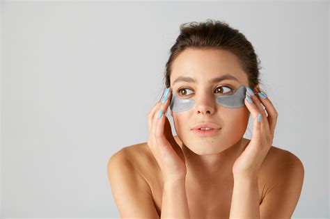 회색 스튜디오 배경에 신선한 모습을 위해 눈 아래 패치를 사용하는 매끄러운 피부를 가진 아름다운 젊은 여성 보습제에 대한 스톡 사진 및 기타 이미지 Istock