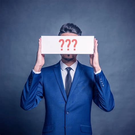 Premium Photo Young Attractive Man In A Blue Suit Holding A White Sign With Red Question Marks