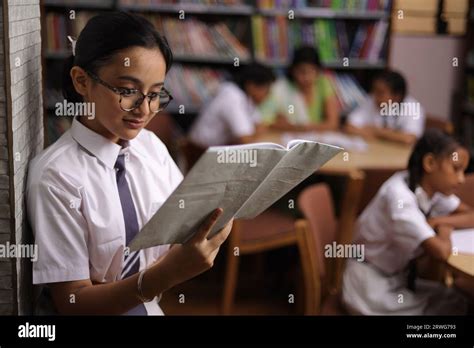 Smart Babe Leaning Against Wall Reading A Book In Hand Focused Nerd Reader In Library