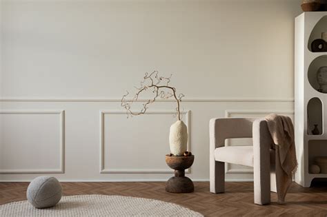 복사 공간 현대적인 안락 의자 가지가있는 꽃병 회색 커피 테이블 둥근 베개 베이지 색 깔개 흰색 랙 및 개인 액세서리가있는 거실