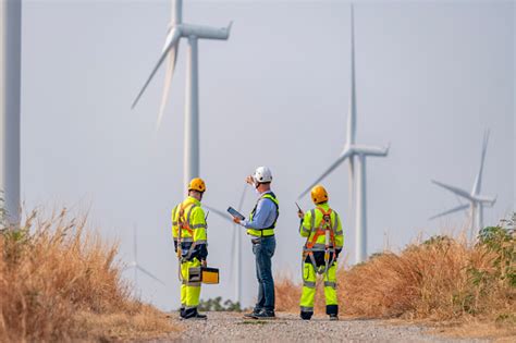 엔지니어 측량사 및 관리자가 유니폼을 입고 보행 상자 검사 및 태블릿을 착용하고 풍력 터빈 농장에서 전기로 순환 청정 전력 에너지 개념을위한 대체 재생 가능 에너지로