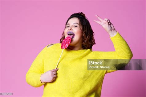 밝은 플러스 크기 모델 큰 롤리팝 분홍색 배경에 노란색 점퍼에 뚱뚱한 여자 건강에 좋지 않은 음식에 대한 스톡 사진 및 기타 이미지 건강에 좋지 않은 음식 곡선 과도