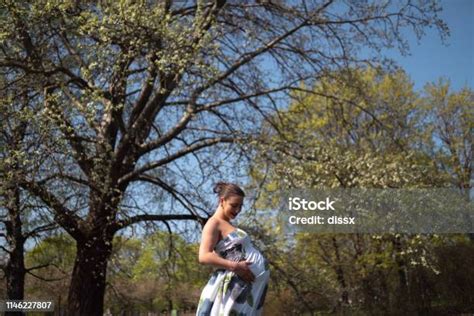 젊은 여행자 임신 한 여자 걷기 달리기 주위를 선회 하 고 꽃 패턴으로 여름 빛 긴 드레스를 입고 꽃 피는 사쿠라 벚꽃 나무 공원에서 그녀의 여가 자유 시간을 즐긴다 개념에