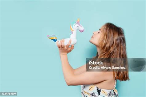 푸른 배경에 여름 상의와 귀여운 키스와 풍선 유니콘 모양의 수영장을 들고 쾌활한 젊은 금발 소녀의 측면 보기 여름 컨셉 복사 공간을 복사합니다 수영장 스포츠 경기장에 대한