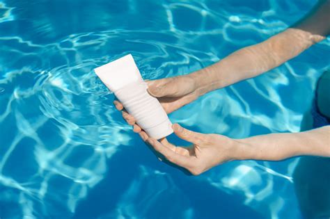 한 젊은 여성이 태양의 그림자가 있는 수영장의 푸른 물 아래에 흰색 크림 튜브를 엽니다 보습 및 자외선 차단제 피부 화장품의 개념 공란에 대한 스톡 사진 및 기타 이미지