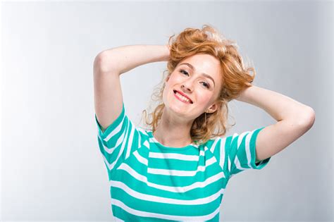 회색 배경에 스튜디오에 블루 스트립 여름 드레스에 붉은 곱슬 머리를 가진 젊은 아름 다운 여자의 클로 우즈 업 초상화 여름 휴가 관광 및 여름 옷의 테마 곱슬 머리에 대한