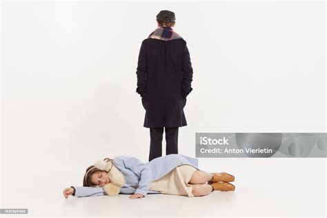 겨울 코트를 입은 젊은 여성이 바닥에 누워 자고 있는 모습 하얀 배경 위에 그녀의 뒤에 서 있는 남자의 초상화 25 29세에 대한 스톡 사진 및 기타 이미지 Istock