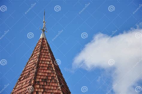 Historic Tower With Triangular Roof Against Blue Sky And Single White