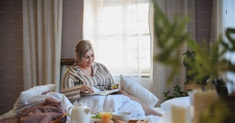 헤드폰과 스마트폰을 들고 집에서 침대에서 아침 식사를 하는 행복한 과체중 여성 사진 Unsplash의 플러스 사이즈 이미지