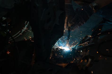 클로즈업 보기 강한 사람은 용접기 금속 제품은 차고 작업장에서 용접 기계와 용접 파란색과 오렌지 불꽃은 차체 수리 자동차 동안