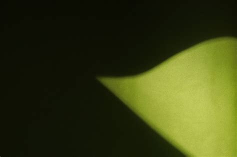 녹색 배경에 빛과 그림자의 놀이 어두운 영역과 밝은 영역은 부드러운 선과 기하학적 전환이 있는 추상적인 패턴을 형성합니다 그래픽 디자인의 배경 0명에 대한 스톡 사진 및